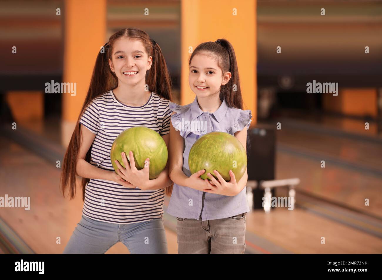 Happy girls with balls in bowling club Stock Photo - Alamy