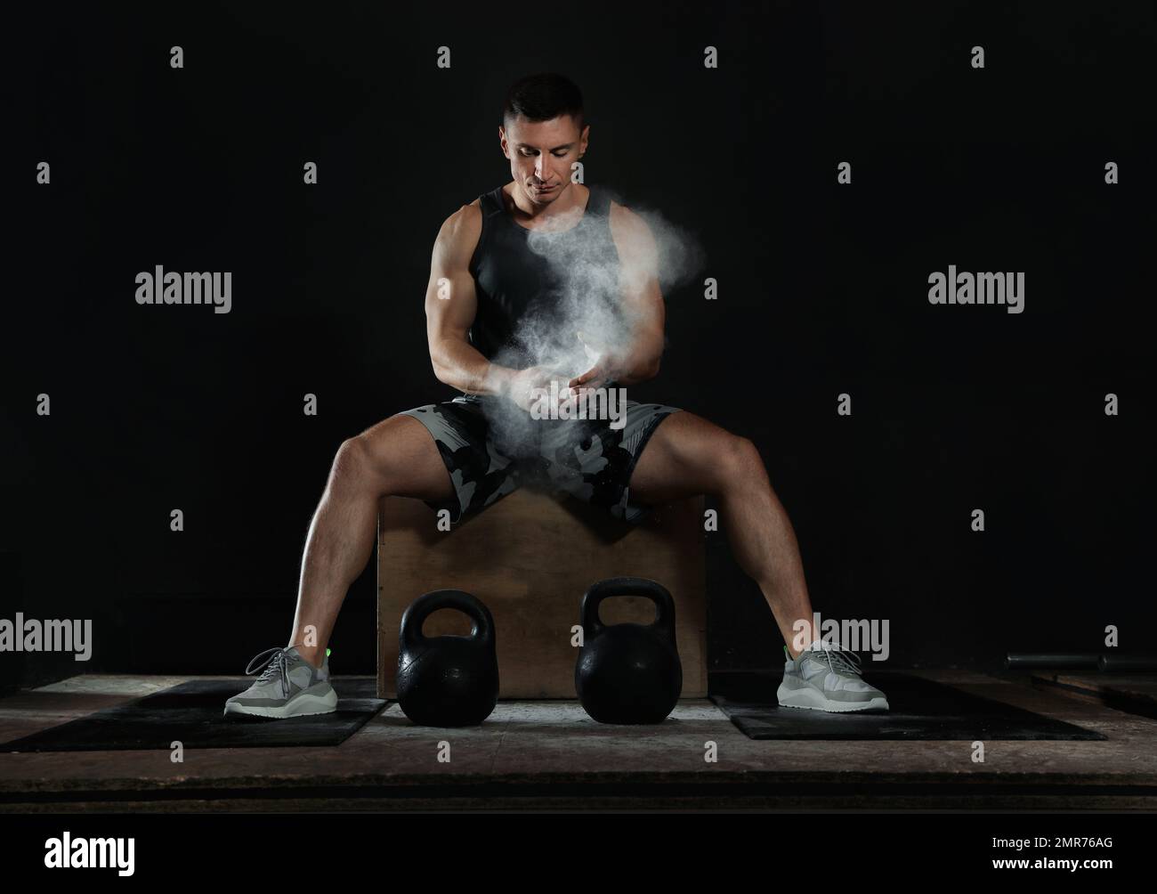 Strong man applying magnesium powder on hands before training with ...