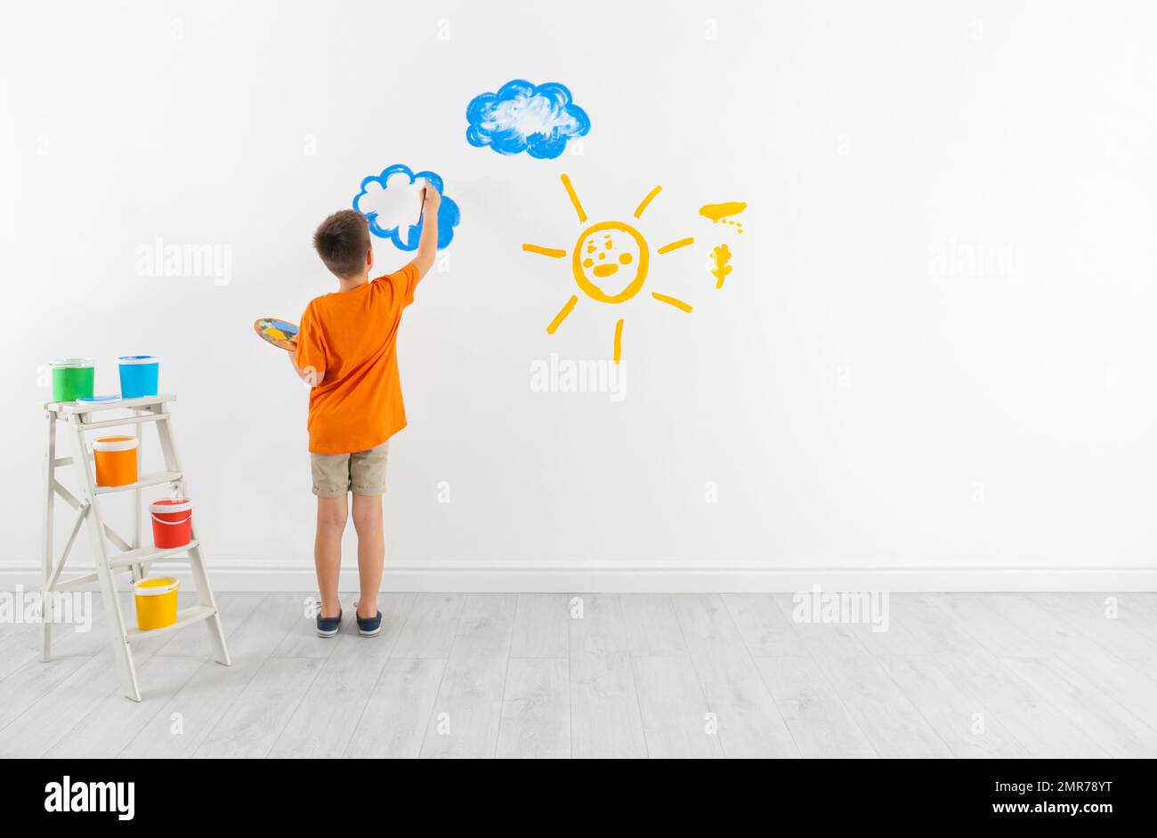 Little child painting cloud on white wall in room Stock Photo - Alamy