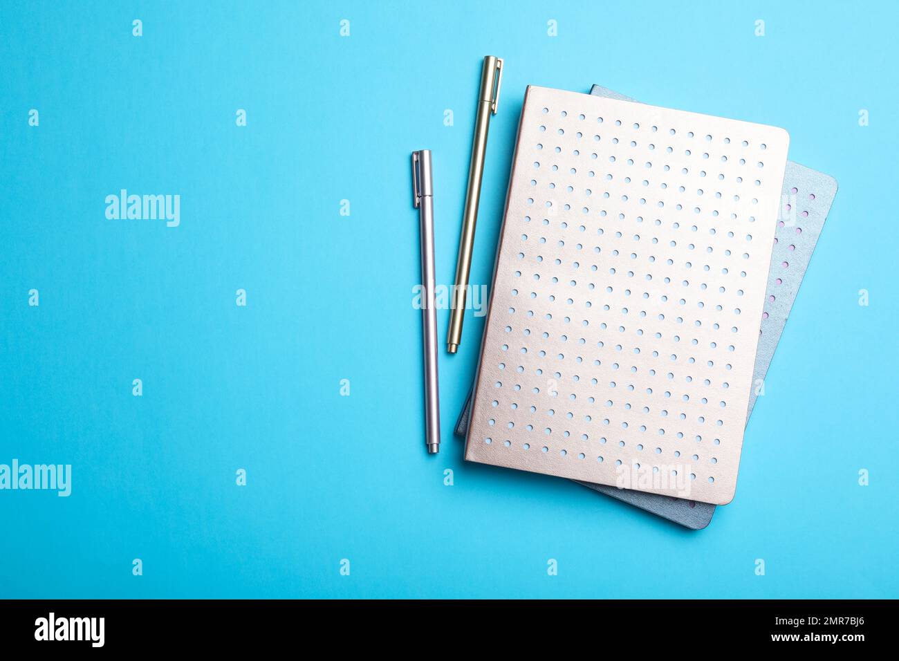 Stylish notebooks and pens on light blue background, flat lay. Space ...