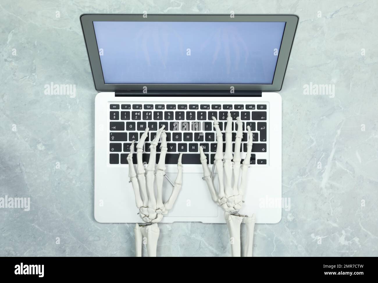 Human skeleton using laptop at grey marble table, top view Stock Photo ...
