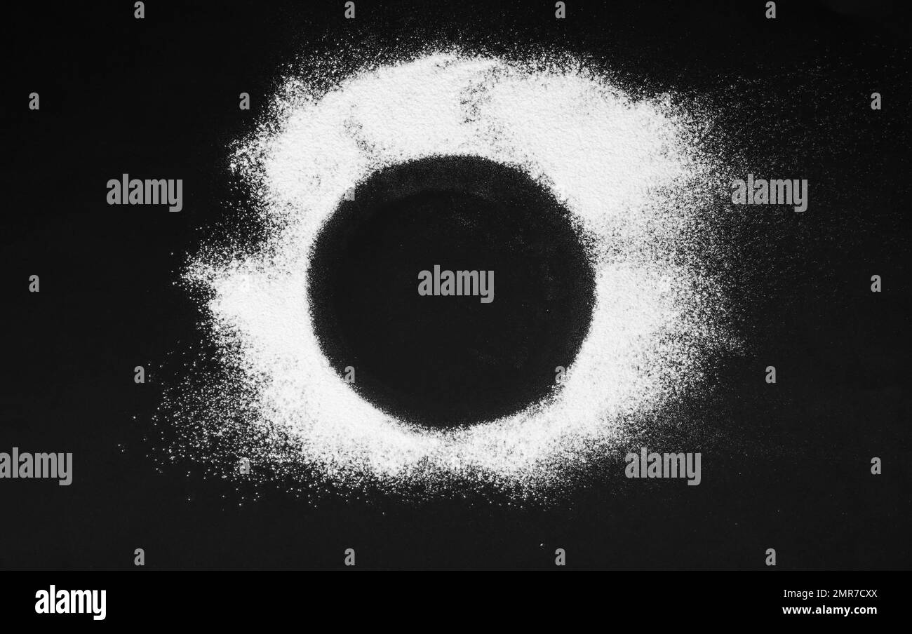 Round frame made of flour on black table, top view. Space for text ...