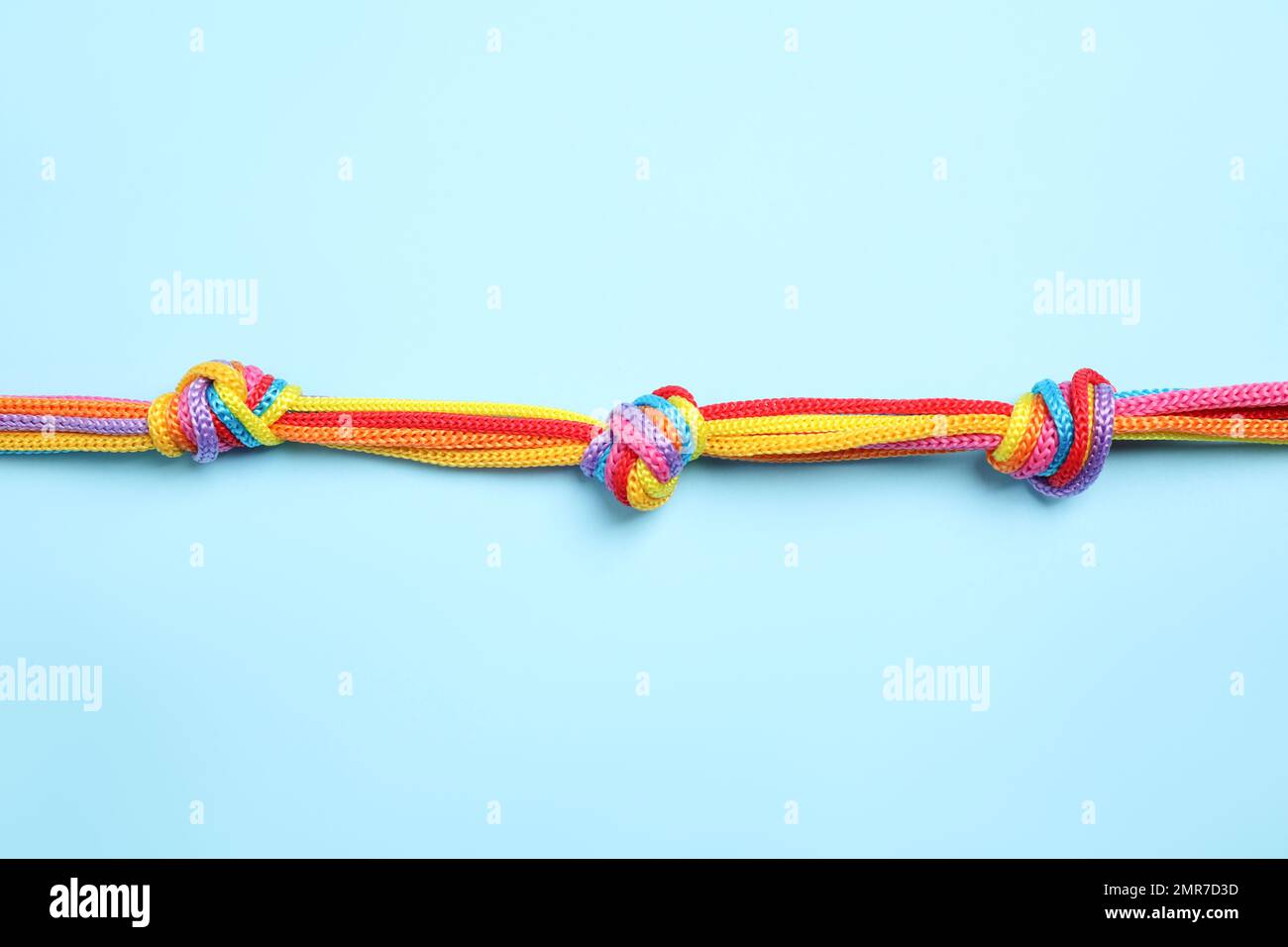 Colorful ropes tied together on light blue background, top view. Unity ...