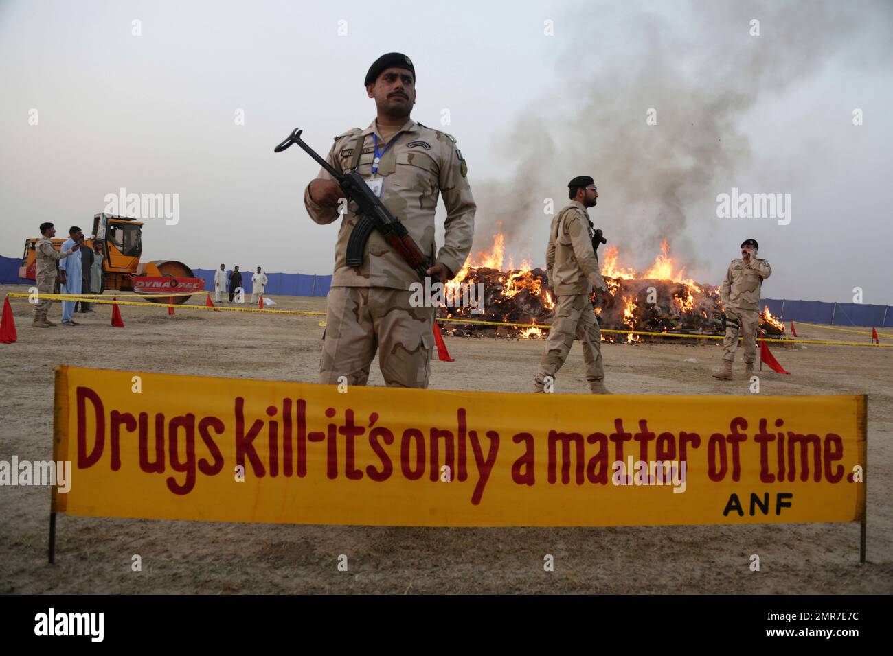 Officers of the Pakistan Anti-Narcotic Force stand near a burning pile ...