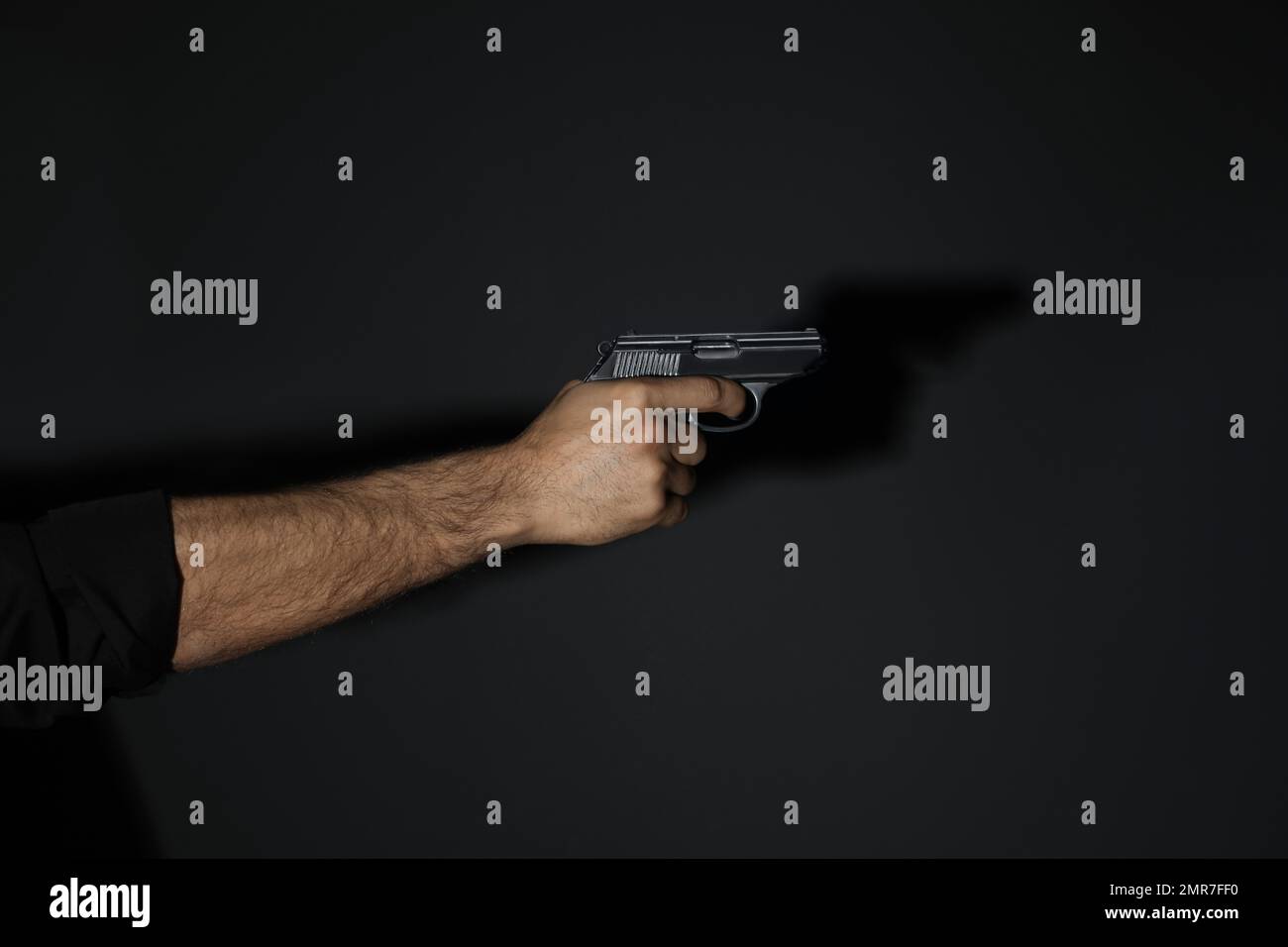 Professional killer with gun on black background, closeup Stock Photo ...