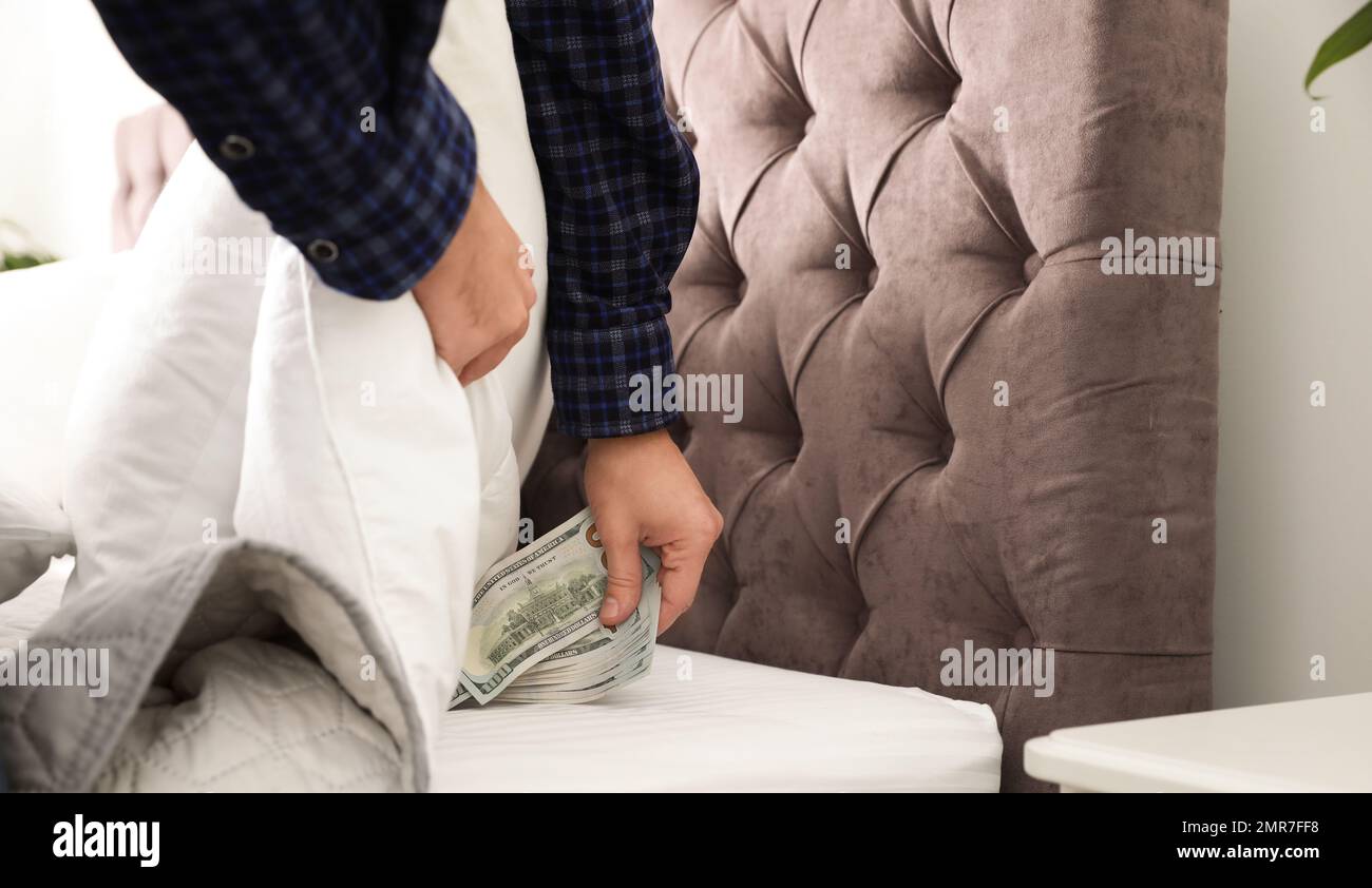 Man hiding dollar banknotes under blanket in bedroom, closeup. Money ...