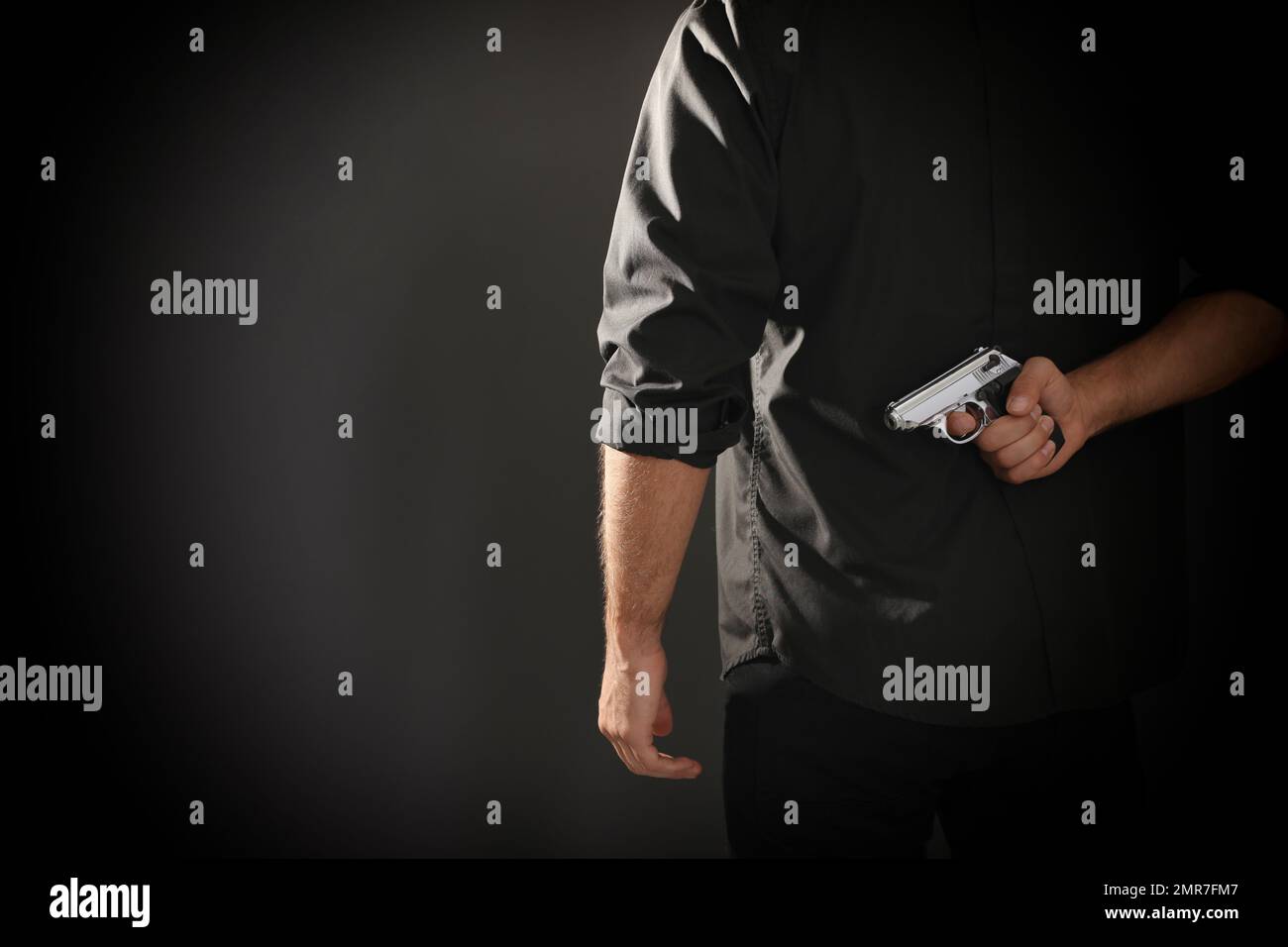 Professional killer with gun on black background, closeup. Space for ...