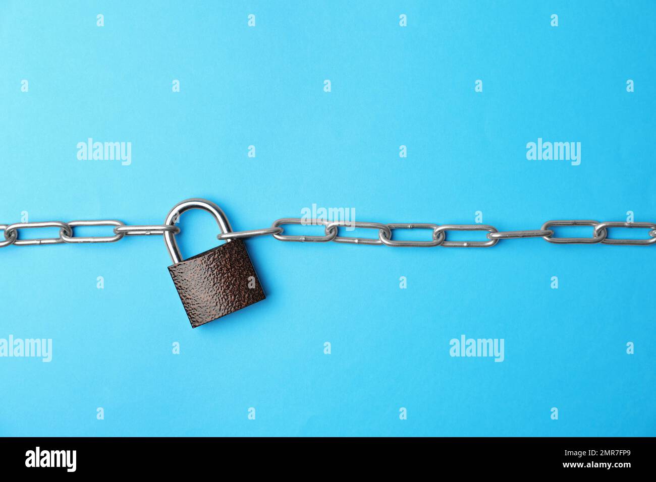 Steel padlock and chain on light blue background, top view. Safety ...