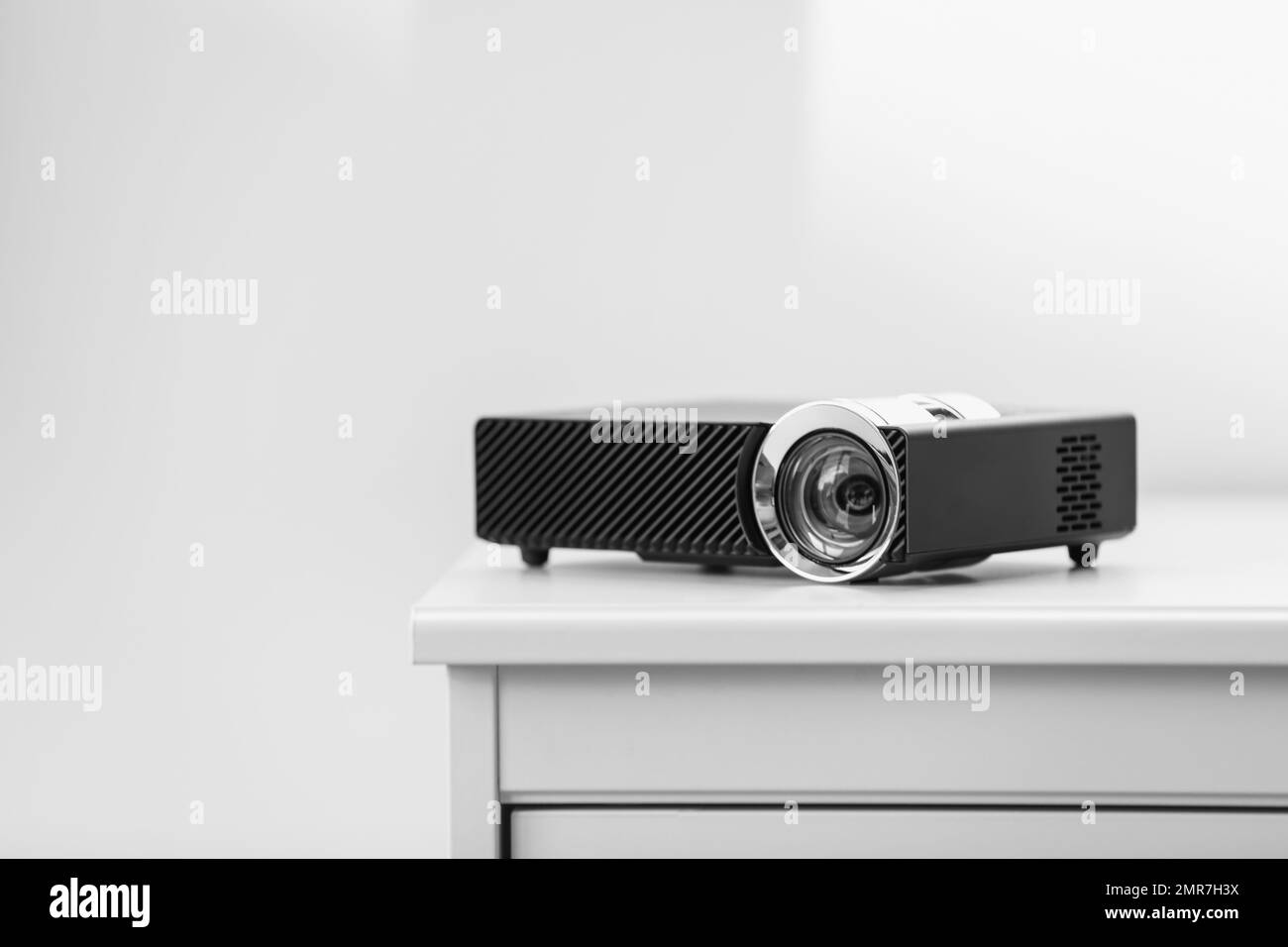 Modern video projector on white table indoors Stock Photo - Alamy