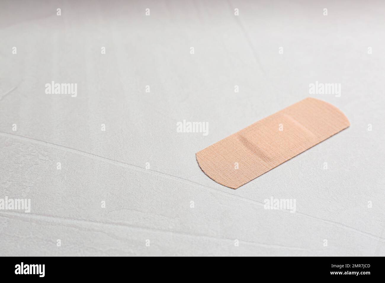 Medical sticking plaster on light stone background. Space for text ...