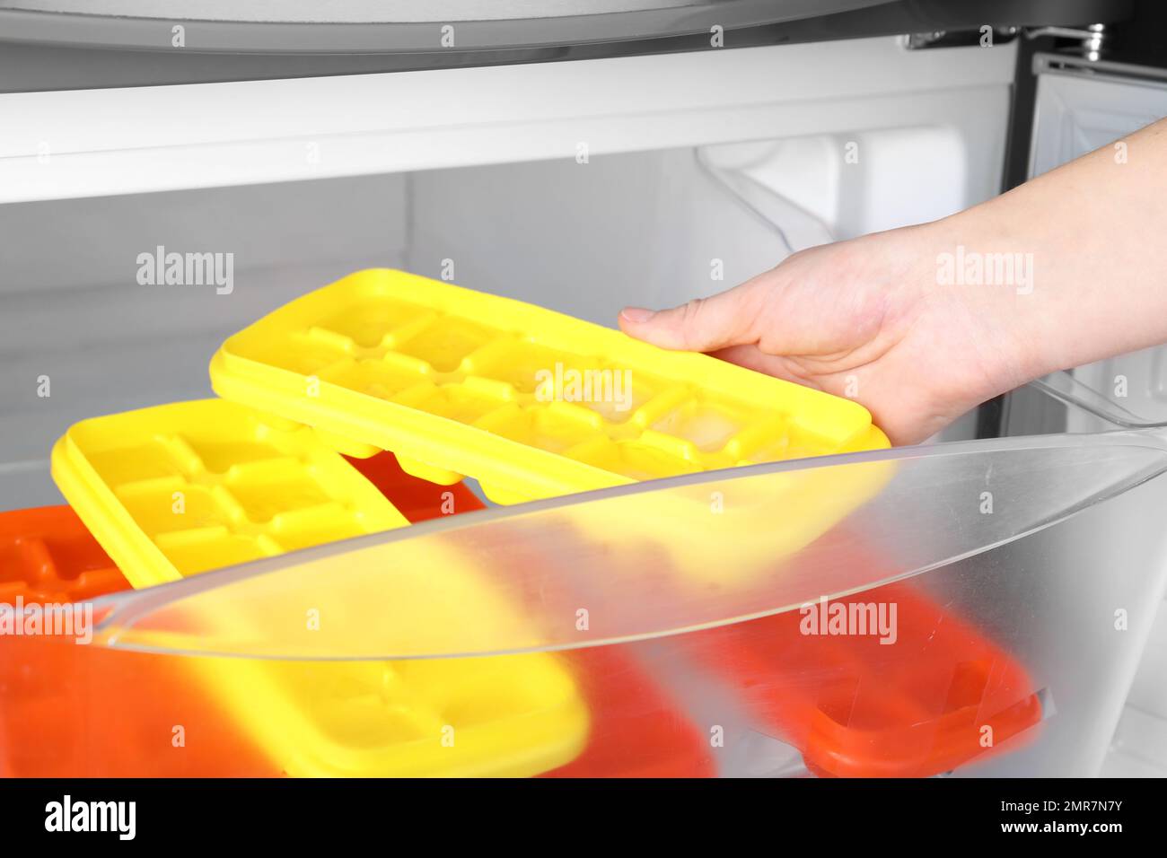 Woman taking tray with ice cubes from fridge, closeup Stock Photo - Alamy