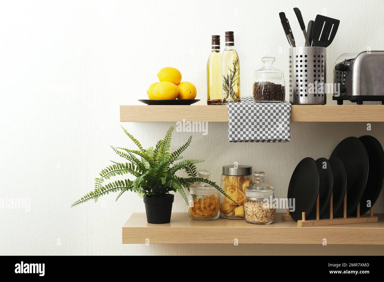 Wooden shelves with dishware and products on white wall. Kitchen ...