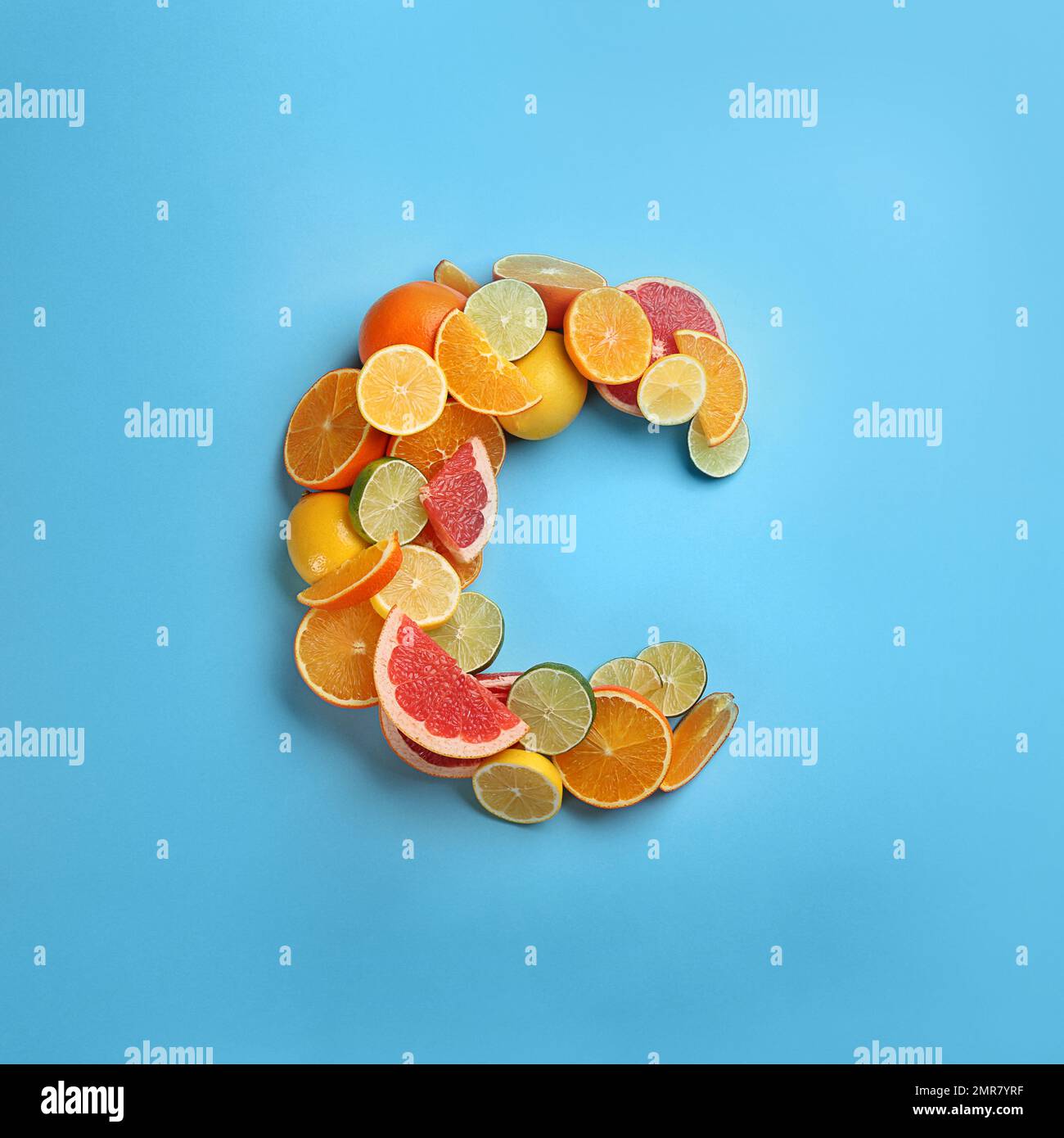 Letter C made with citrus fruits on light blue background as vitamin ...