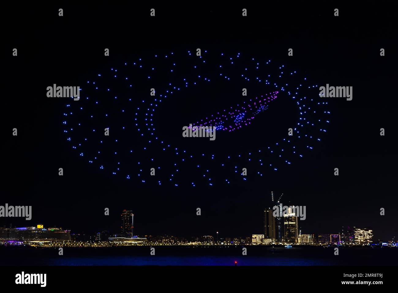 The illuminated blue drones glowing in the black night sky and forming ...