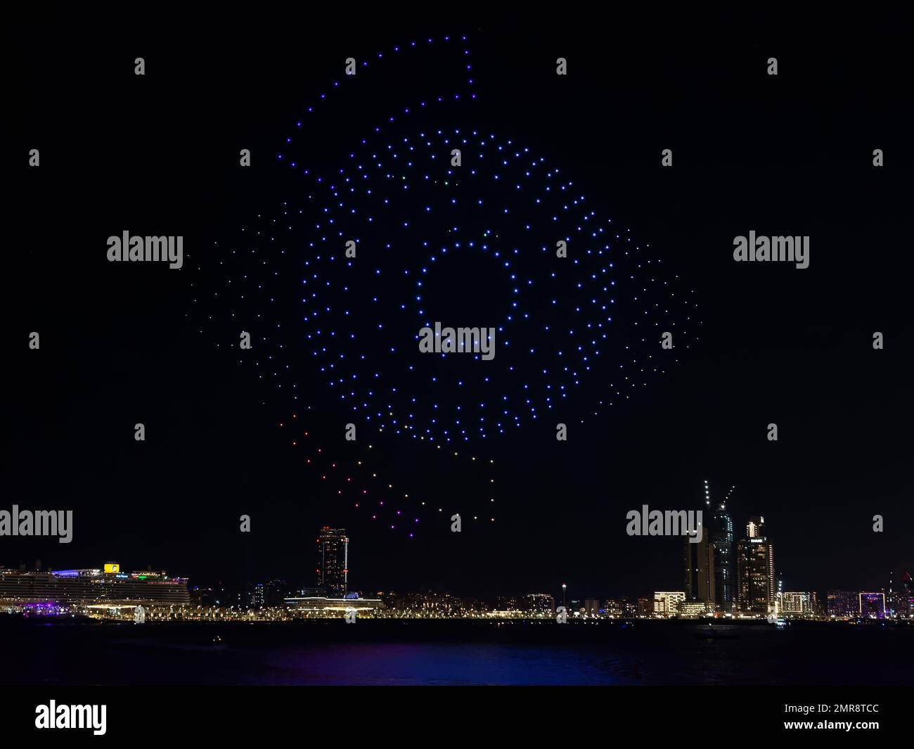 The illuminated blue drones glowing in the black night sky and forming ...