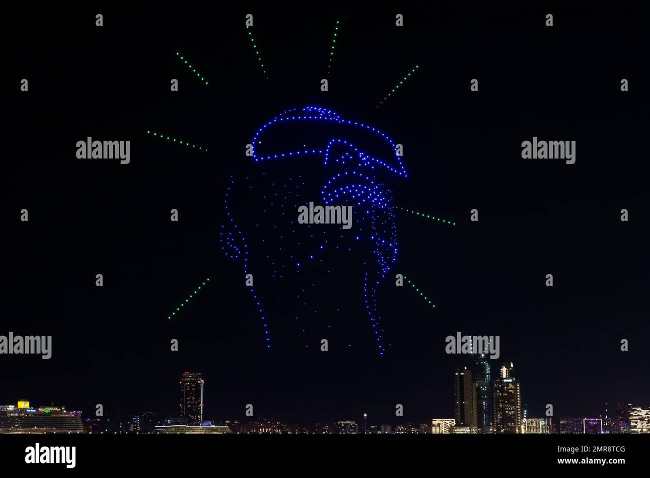 The illuminated blue drones glowing in the black night sky and forming ...