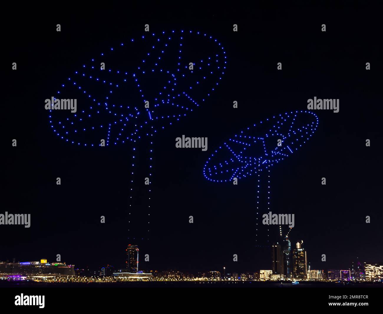 The illuminated blue drones glowing in the black night sky and forming ...