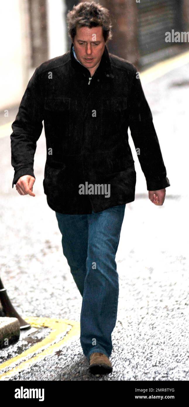 Hugh Grant walks the rainy streets of London with a pal. London, UK. 02 ...