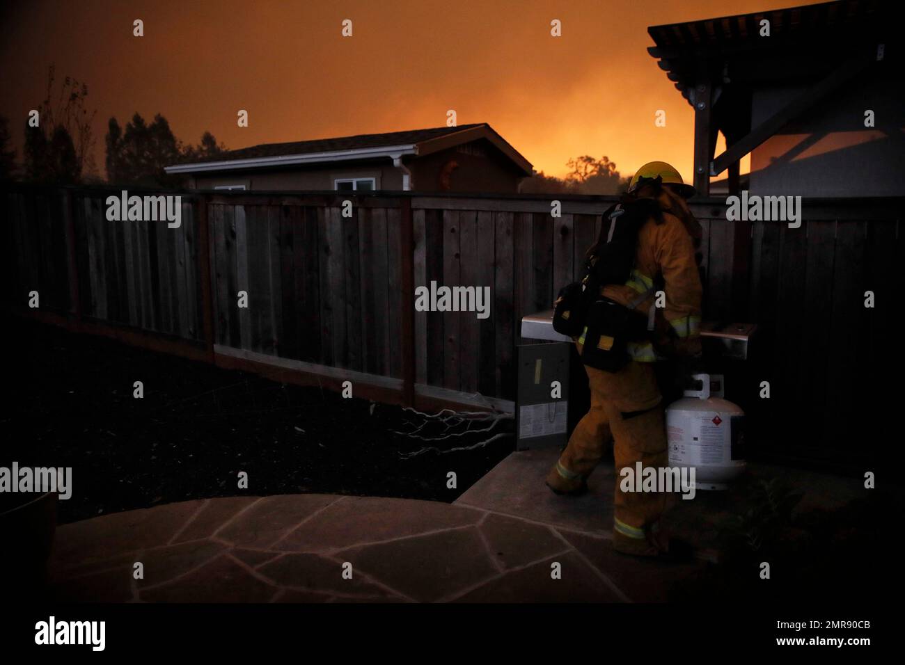 A firefighter removes a propane gas tank in an evacuated residential ...