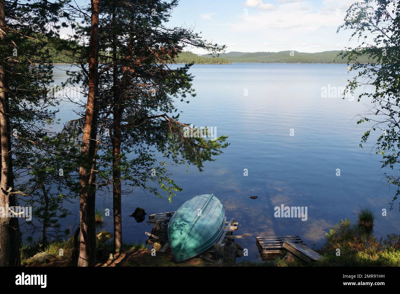 Small boat lying on a deserted lake, trees, summer, Lapland, Inari ...