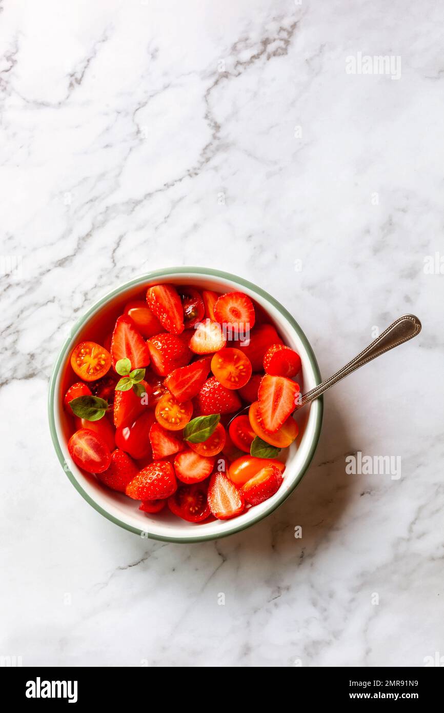 bowl of strawberry, tomato cherry and basil leaves salad, top view ...