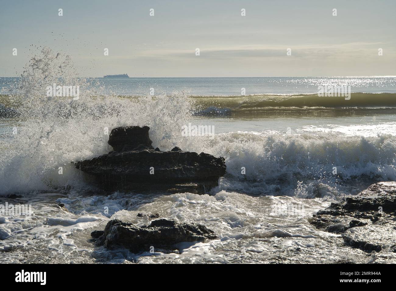 A beautiful view of rocks on a shore with splashing waves during ...