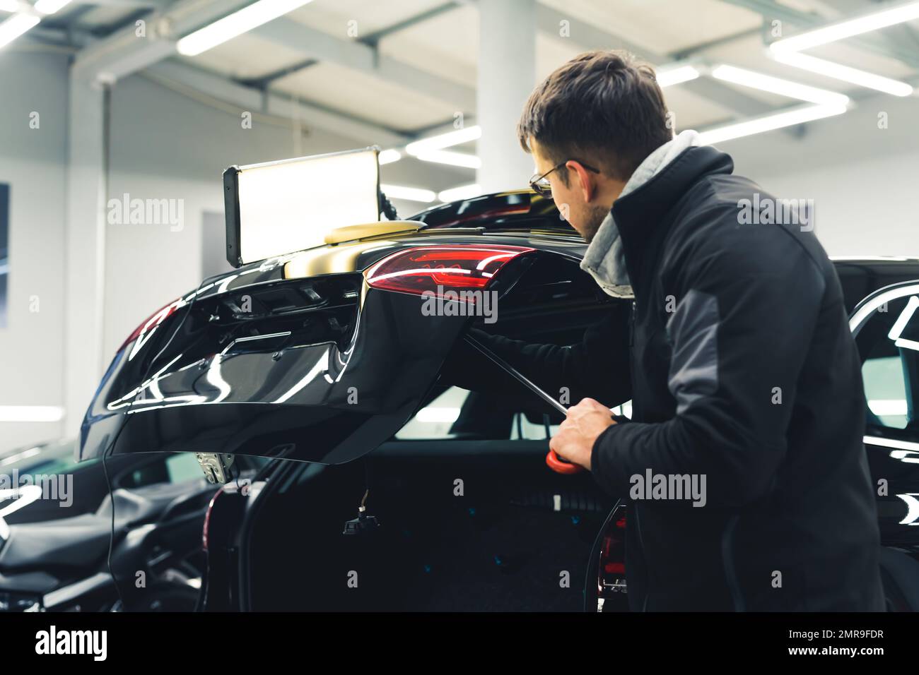 Technician repairing dent on trunk. Process of repairing damaged car in ...