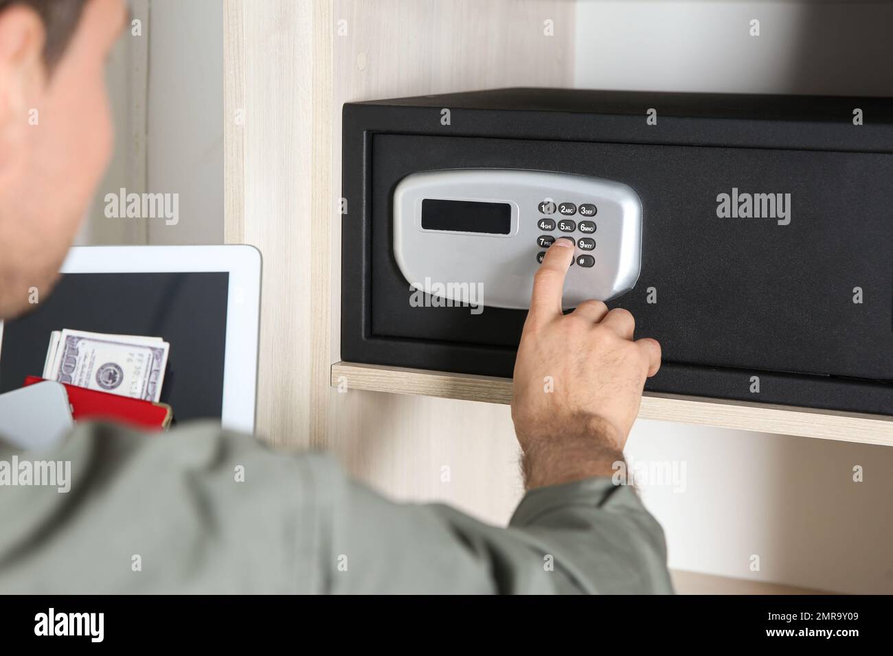 Man opening black steel safe with electronic lock at hotel, closeup ...