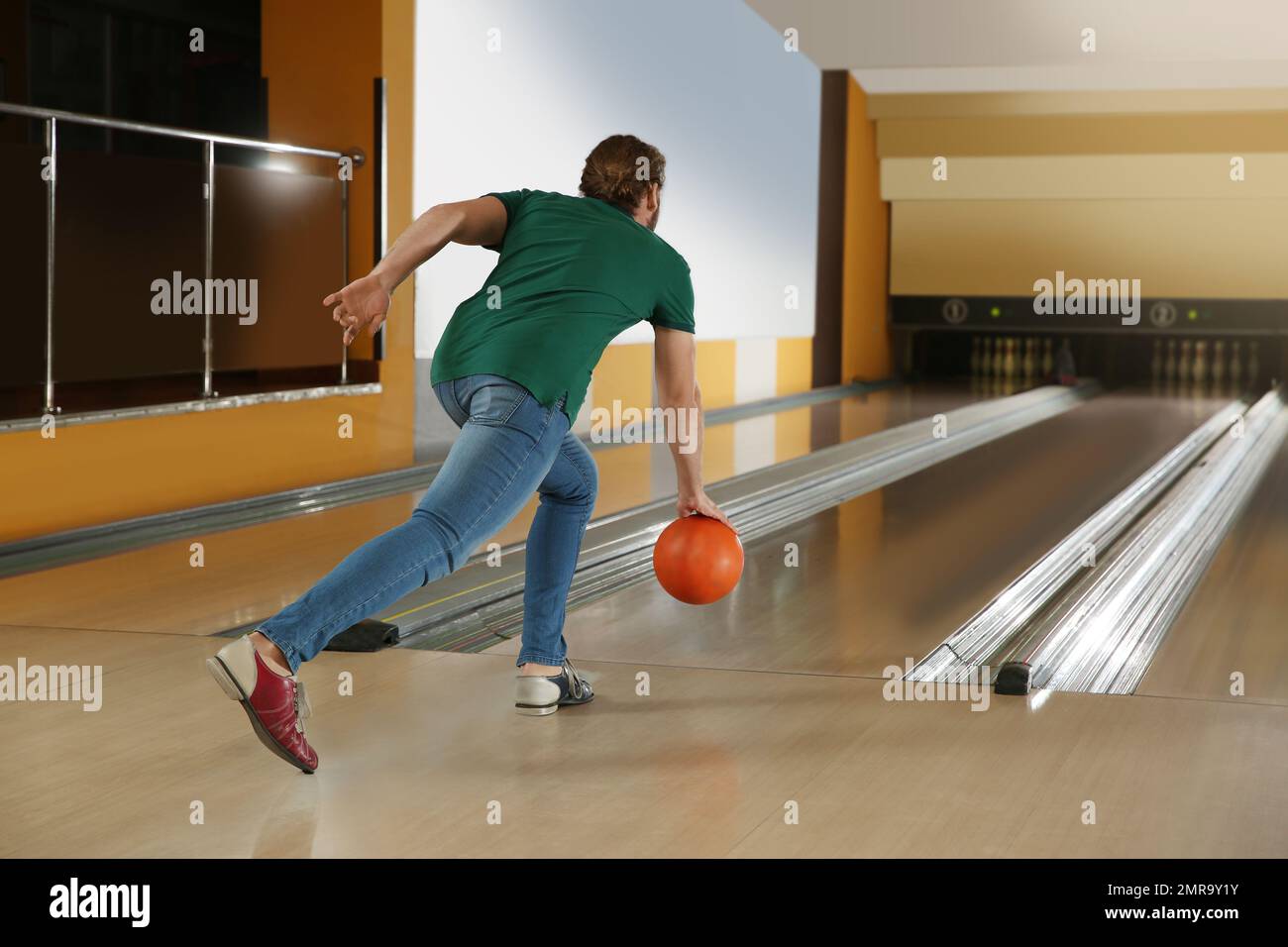 Young man throwing ball in bowling club Stock Photo - Alamy