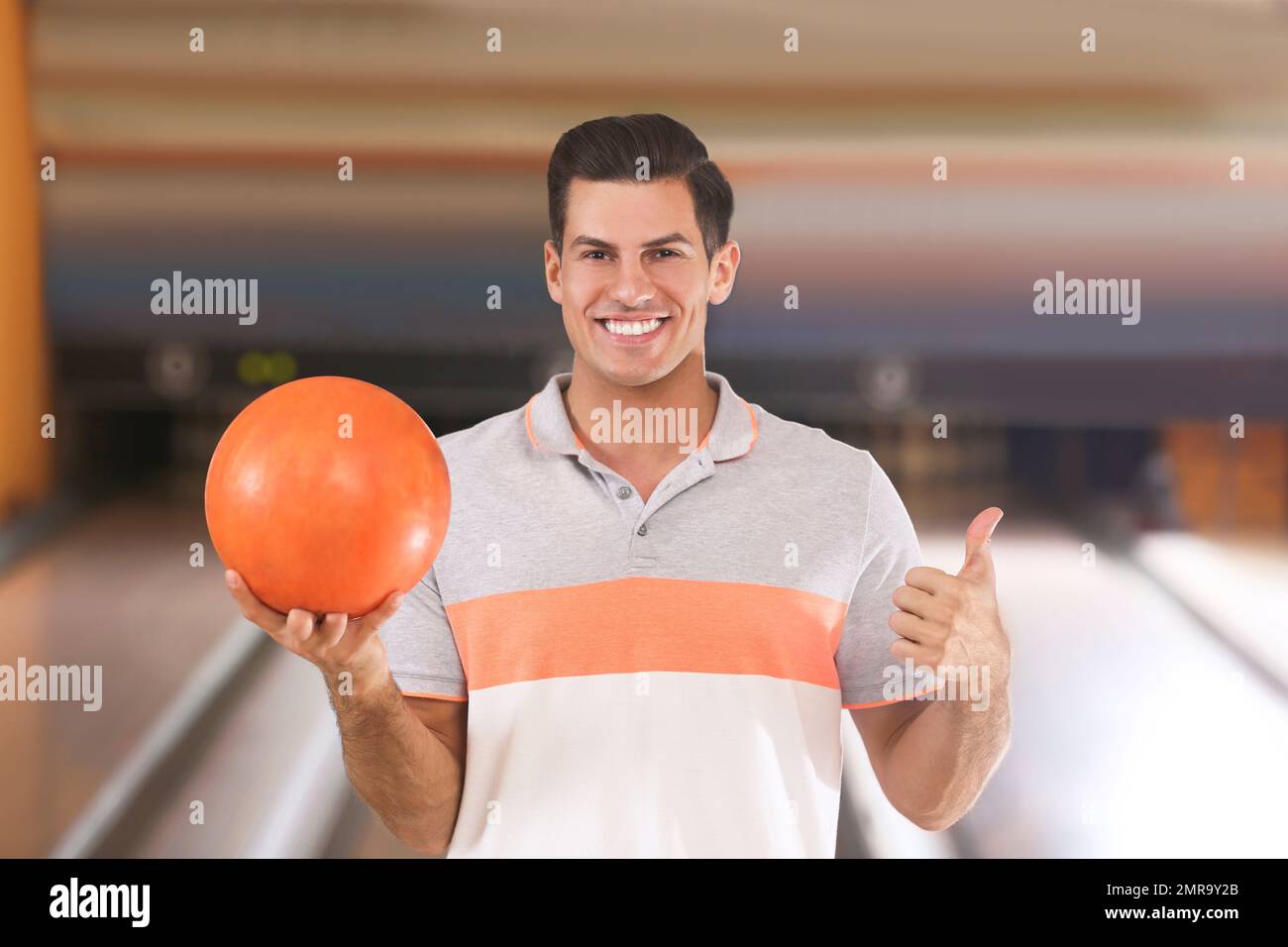 Man with ball in modern bowling club Stock Photo - Alamy