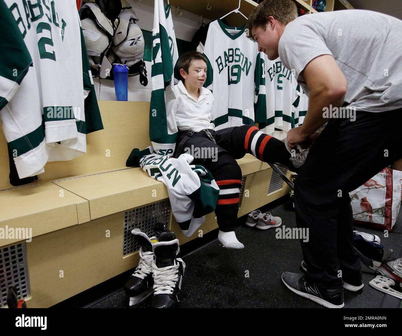 Coleman Walsh, 10, of Walpole, Mass., left, is assisted with his skates ...