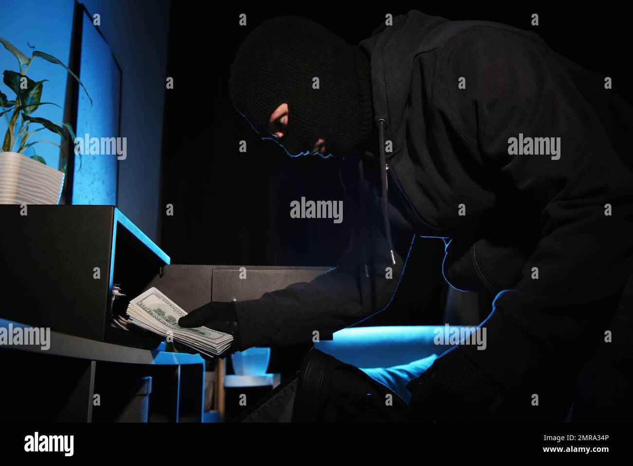 Thief taking money out of steel safe indoors at night Stock Photo - Alamy
