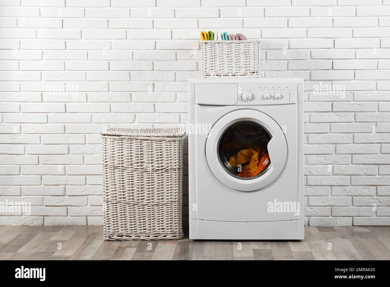 Modern washing machine and laundry baskets near white brick wall Stock ...