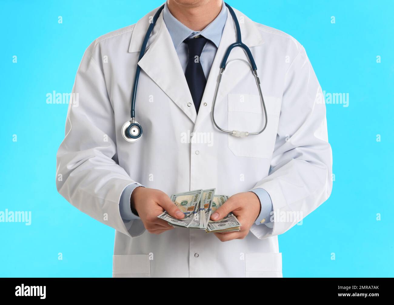 Doctor with bribe on light blue background, closeup. Corruption in ...