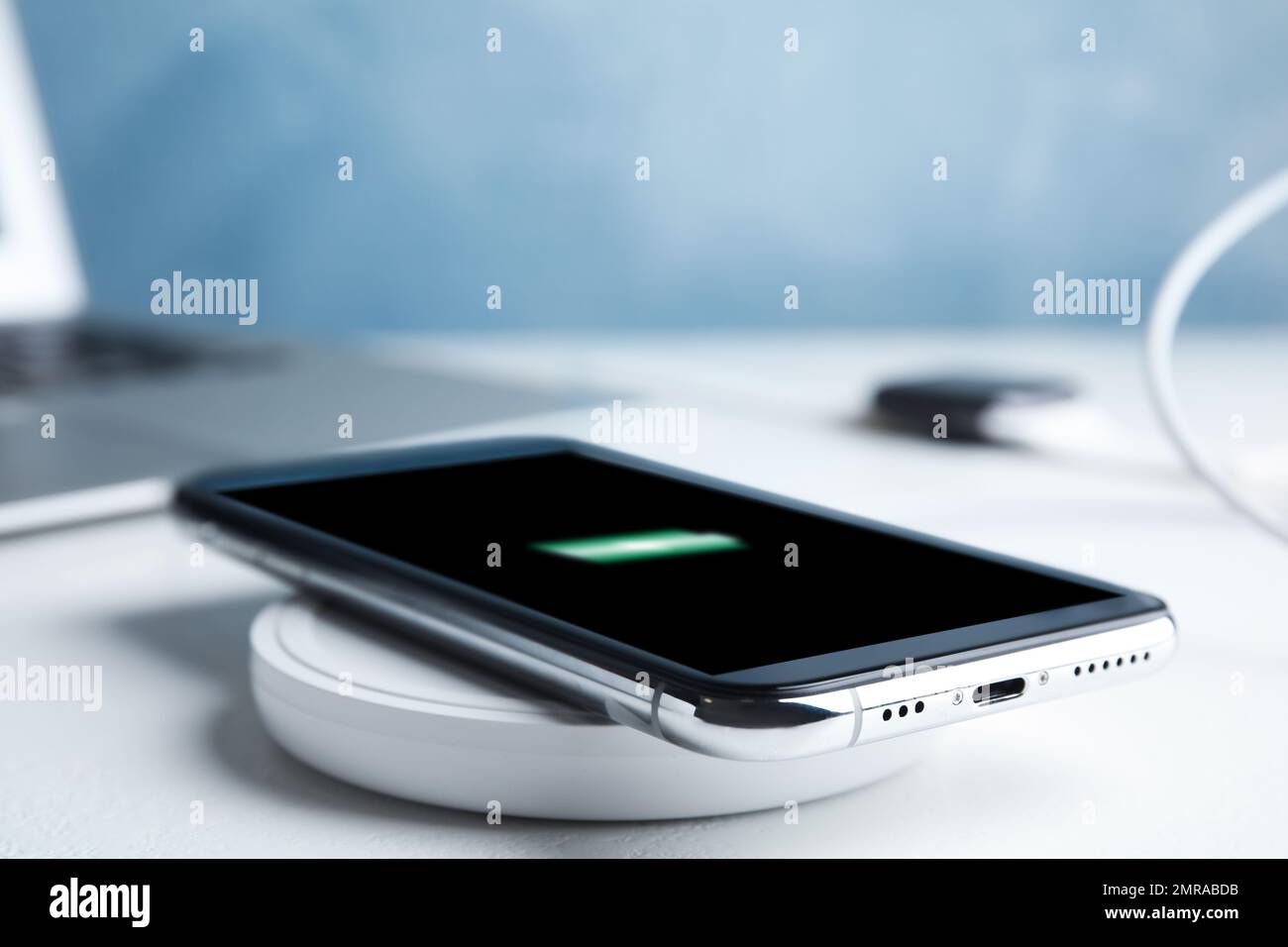 Mobile phone charging with wireless pad on white stone table, closeup ...