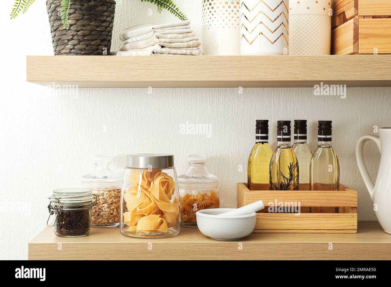 Wooden shelves with dishware and products on white wall. Kitchen ...