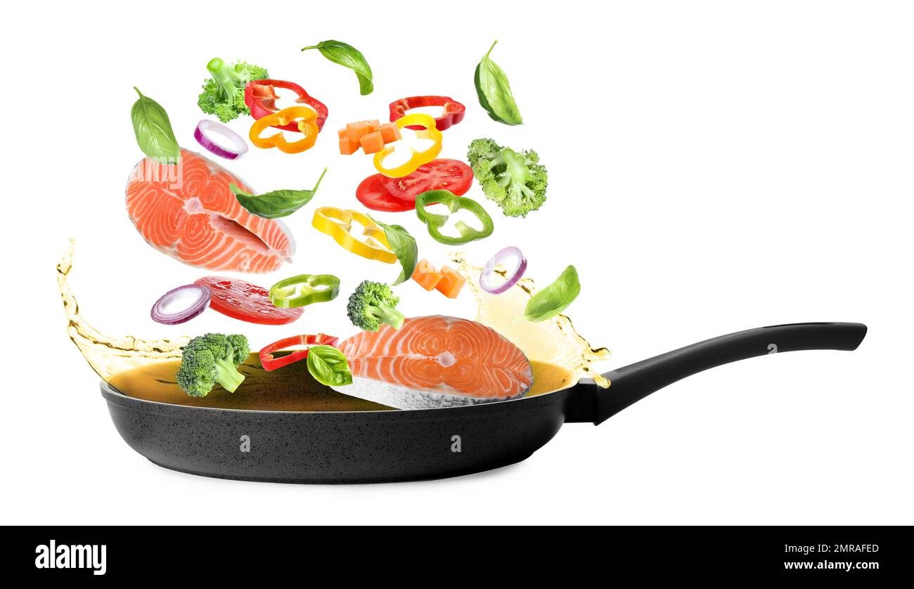 Many different ingredients falling into frying pan on white background ...