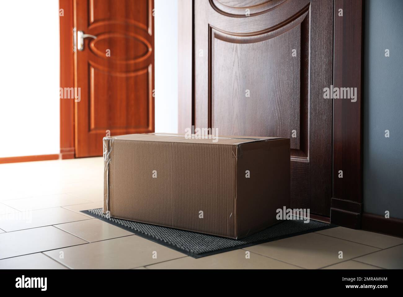 Cardboard box on rug near door. Parcel delivery service Stock Photo - Alamy