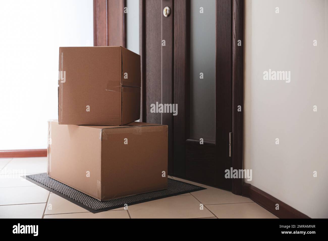 Cardboard boxes on rug near door. Parcel delivery service Stock Photo ...