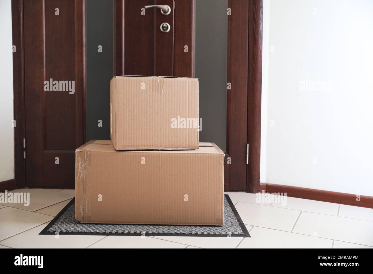 Cardboard boxes on rug near door. Parcel delivery service Stock Photo ...