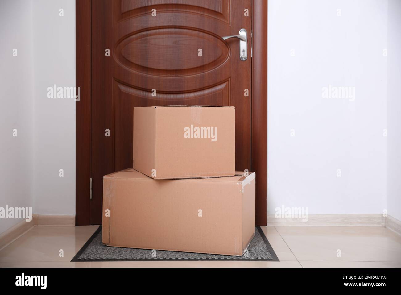 Cardboard boxes on rug near door. Parcel delivery service Stock Photo ...