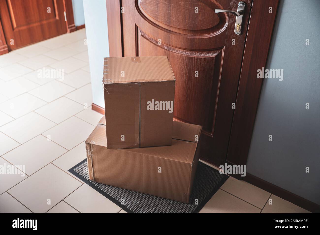 Cardboard boxes on rug near door. Parcel delivery service Stock Photo ...