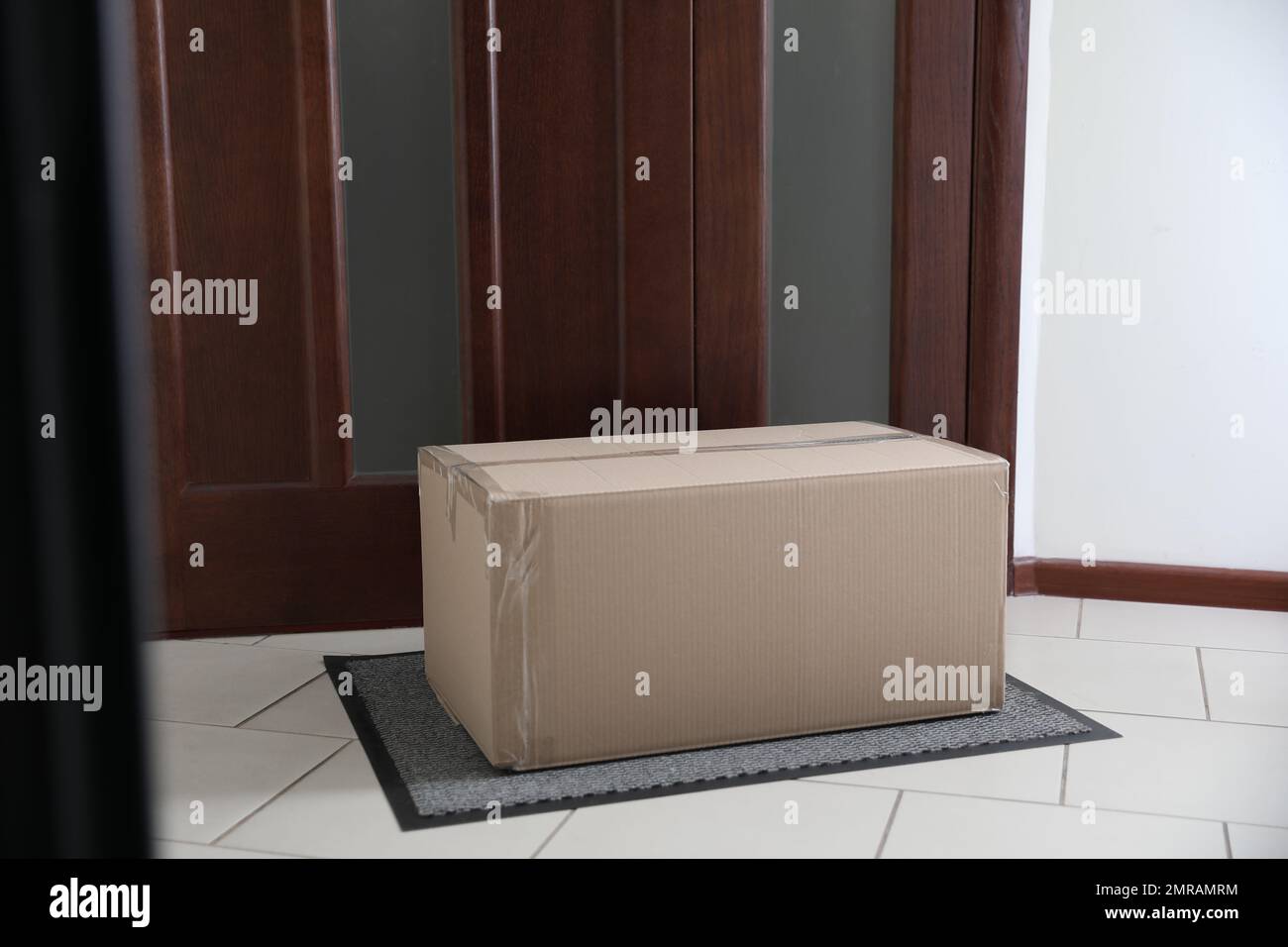 Cardboard box on rug near door. Parcel delivery service Stock Photo - Alamy