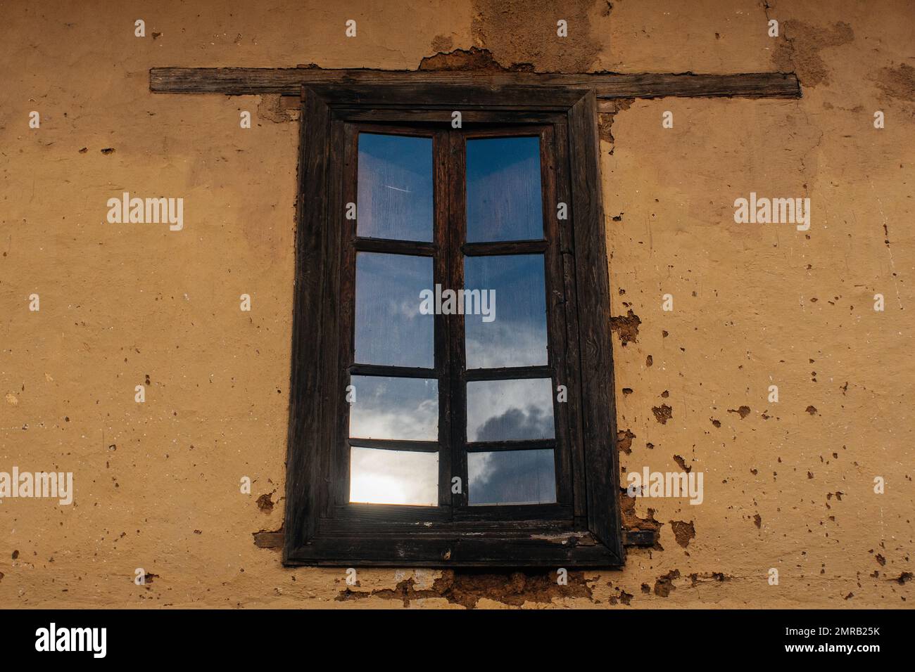 An old wooden window with rusty frames, sky and sunlight seen through ...