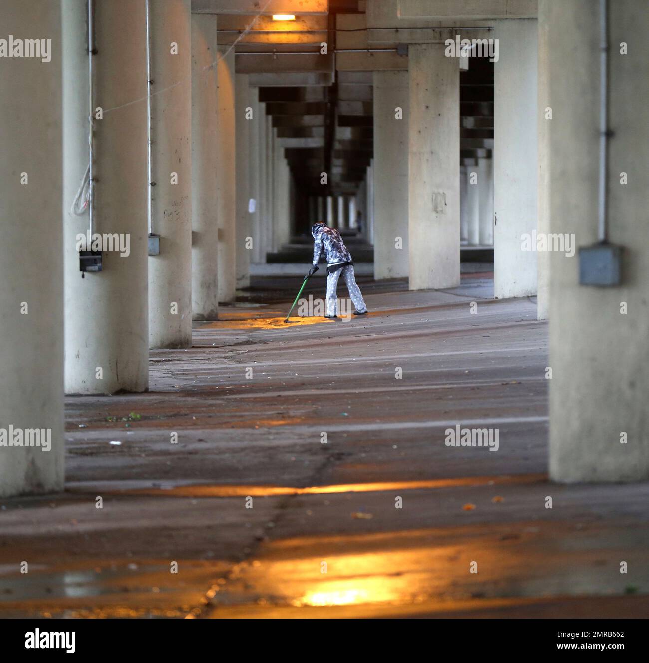 A homeless woman mops the area she was staying, as sanitation employees ...