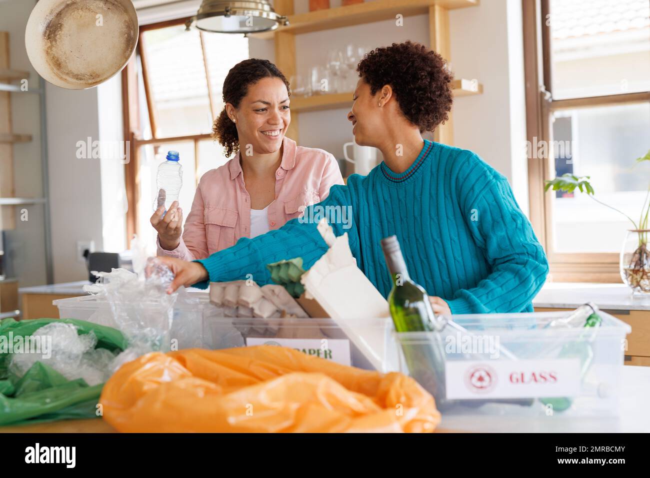 Happy diverse female couple segregating waste in kitchen Stock Photo ...
