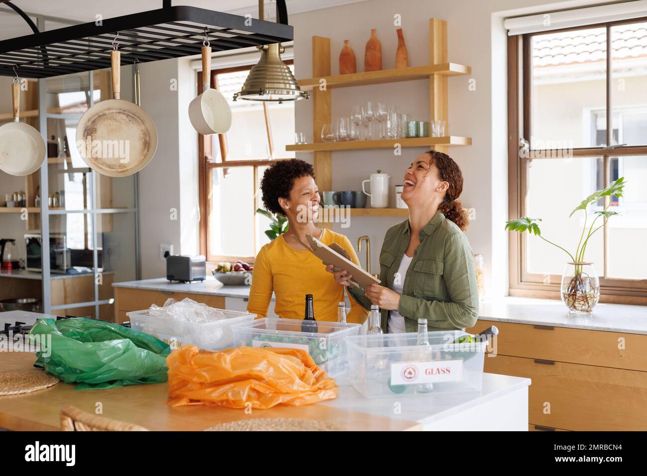 Happy diverse female couple segregating waste in kitchen Stock Photo ...