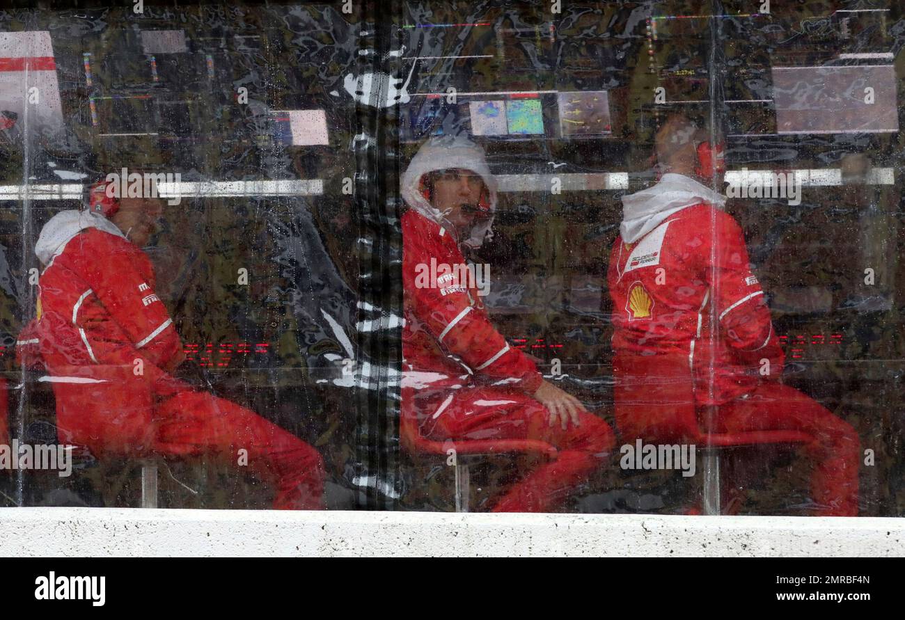 Ferrari team members work in the rain during the second practice ...