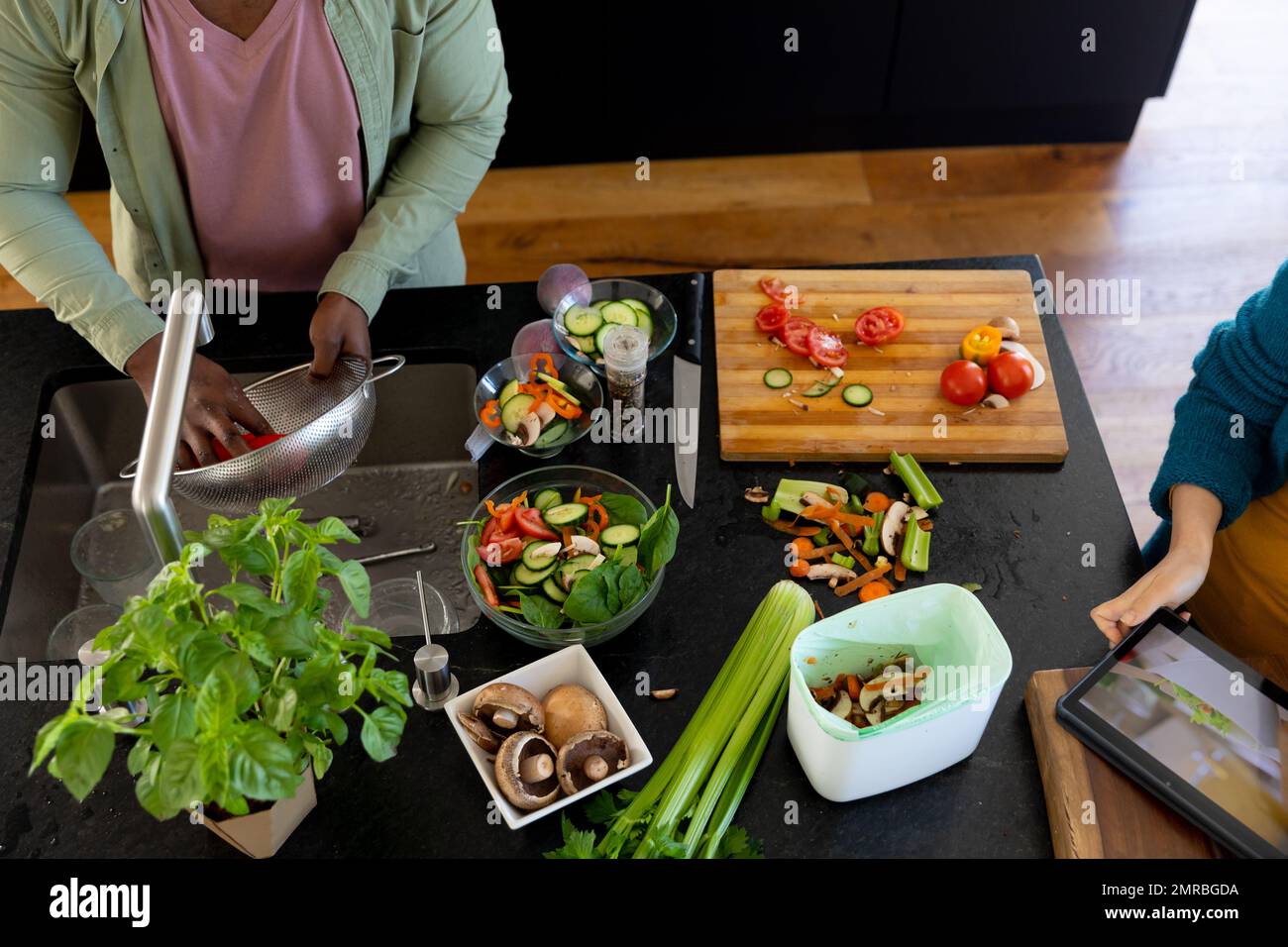 High angle of diverse couple preparing food, using tablet and ...