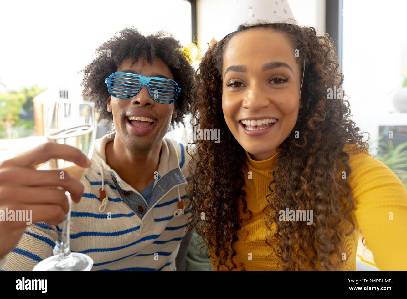 Rear view of happy biracial couple making celebration video call on ...